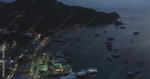 Aerial Island Bay Dusk Harbour Lights Decline View. Sailboat Anchored Dock Area Seaside Resort Mount Hill Background. Yacht Cruise Ocean Tide Calm Waves Isle Coast Nautical Navigation Thailand 4K