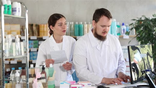 Male and girl pharmacists employee using computer, remote document flow. Worker checks invoice and actual availability of drugs, checks incoming data on tablets.