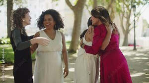 Friends hugging with brides in park after wedding ceremony. Beautiful bridesmaids congratulating lesbian newlyweds, smiling, enjoying moments spending together. LGBT wedding, friendship concept