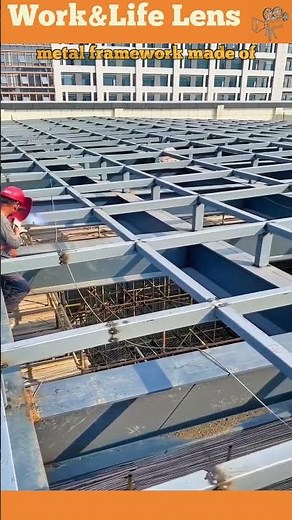 Workers weld a metal grid of rectangular tubing, forming the base or roof of the structure.