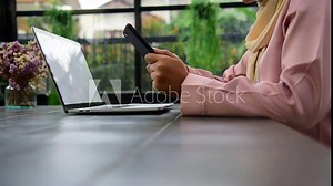 Smiling Muslim woman wear hijab use smart phone digital tablet surf internet work at home office laptop. Muslim woman hijab touch smartphone type laptop keyboard at home office. Empower islam women
