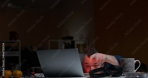 An adult man carefully crawls out from under the table, quickly presses the laptop button and hides. A funny situation
