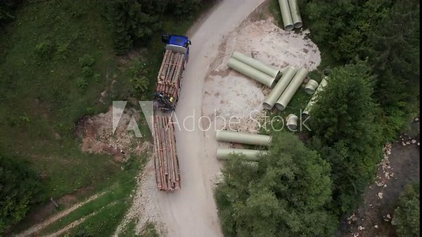 Aerial view of a logging truck transporting cut timber along a forest road. Useful for forestry, industry, environmental impact, sustainability, land use, and deforestation-themed projects.