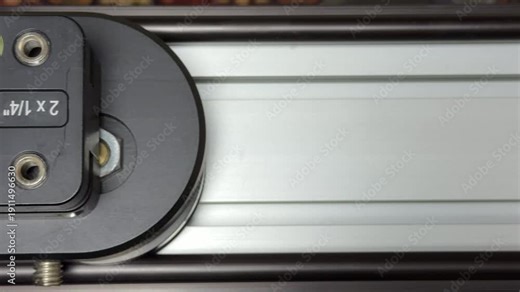 The motorized camera slider activates its internal engine to drive the carriage along the rail. This electrical operation creates a thin, constant mechanical whining sound as the system glides.