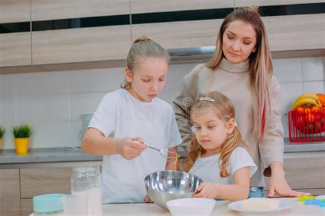 Mom Teaches Her Daughters To Make Dough In The Kitchen And Beat Eggs