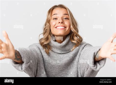 Close Up Of Cute Blond Girl In Grey Sweater Stretching Hands Forward For Hug Receiving