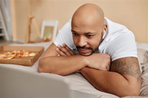 Premium Photo Adult Black Man Watching Videos Via Laptop Laying In Bed At Home