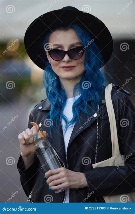 Portrait Of A Stylish Diverse Female Holding A Reusable Glass Bottle Of Water In Hands And