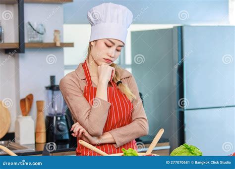Portrait Shot Of Asian Young Beautiful Female Chef Housewife Wears White Tall Cook Hat And Apron