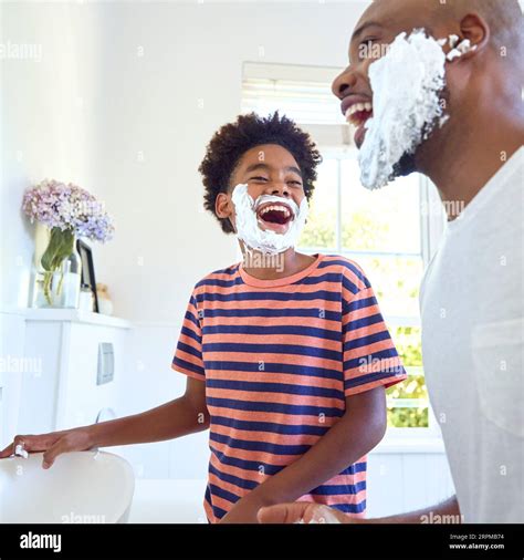 Father And Son At Home Having Fun Playing With Shaving Foam In Bathroom