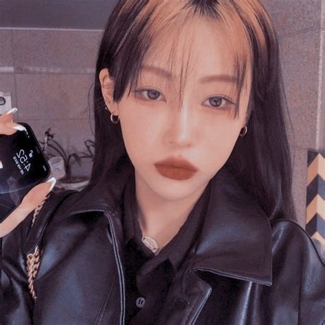 A Woman In Black Leather Jacket Holding Up A Cell Phone