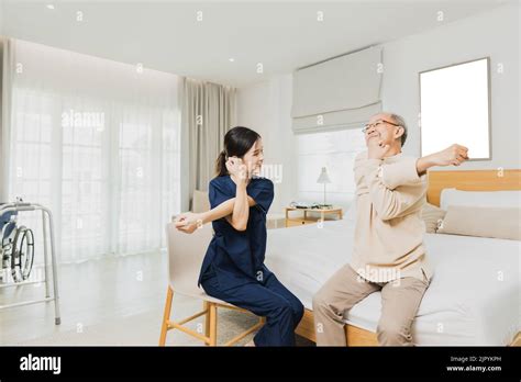 Nurse Woman Assisting Old Man Warming Up Exercises For The Upper Body Inside The Nursing Home