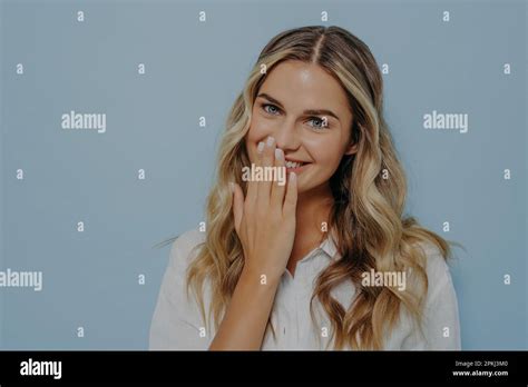 Attractive Shy Blonde Woman Being Flattered While Covering Her Mouth With Hand Does Not Know