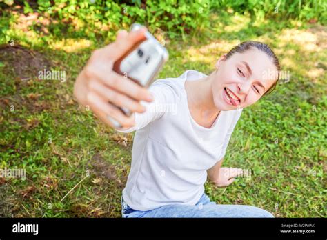 Young Girl Take Selfie From Hands With Phone Showing Tongue And Funny Face Sitting On Park Or