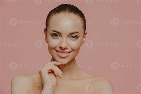 Studio Shot Of Pretty Charming Woman Touches Chin Has Healthy Glowing