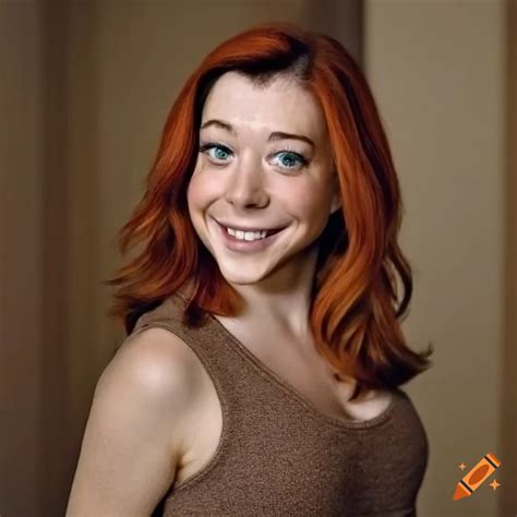 Alyson Hannigan Sitting In A Hotel Room Wearing A Dark Brown Sleeveless Sweater Smiling Sweetly
